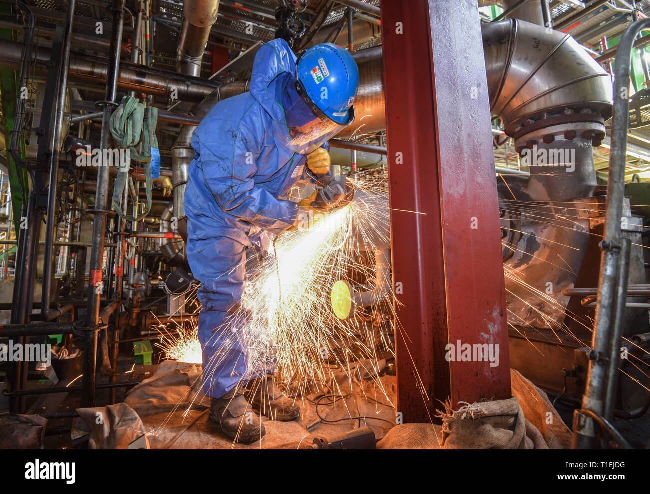 26 March 2019, Brandenburg, Schwedt: A worker uses a cut-off wheel to ...