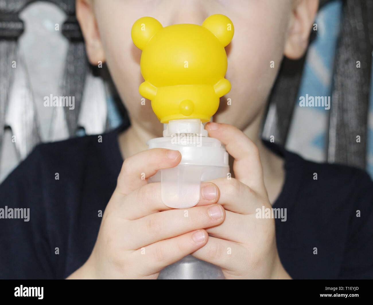 The child makes inhalation. The boy holds in his hand a nebulizer for ...