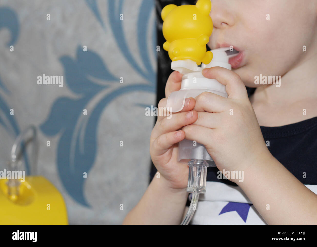 The child makes inhalation. The boy holds in his hand a nebulizer for ...