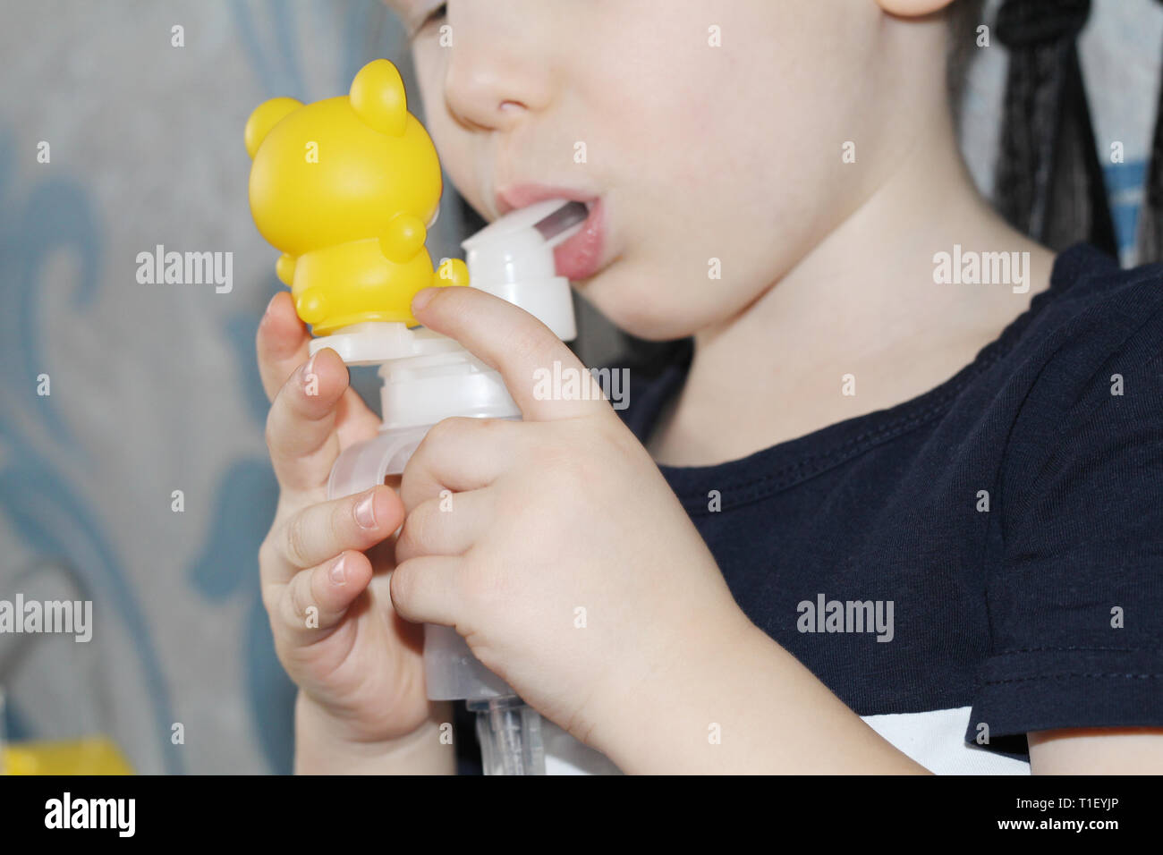 The child makes inhalation. The boy holds in his hand a nebulizer for ...