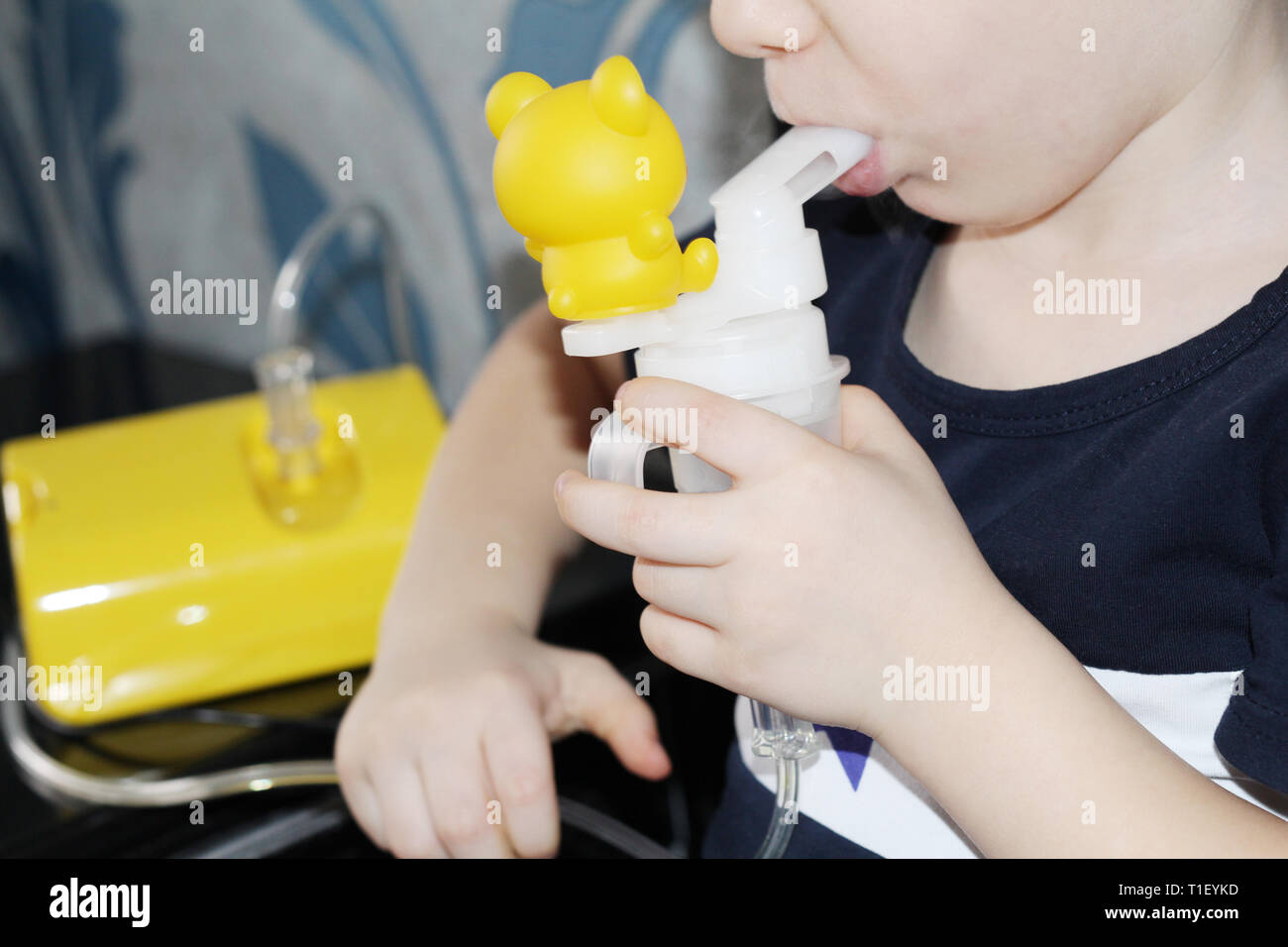 The child makes inhalation. The boy holds in his hand a nebulizer for ...