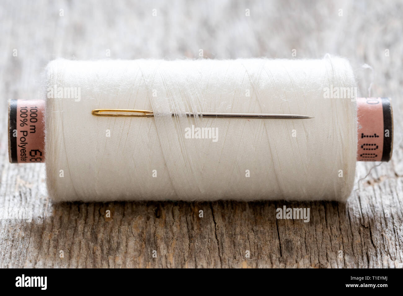 Spool of white thread with a needle on wooden background Stock Photo ...