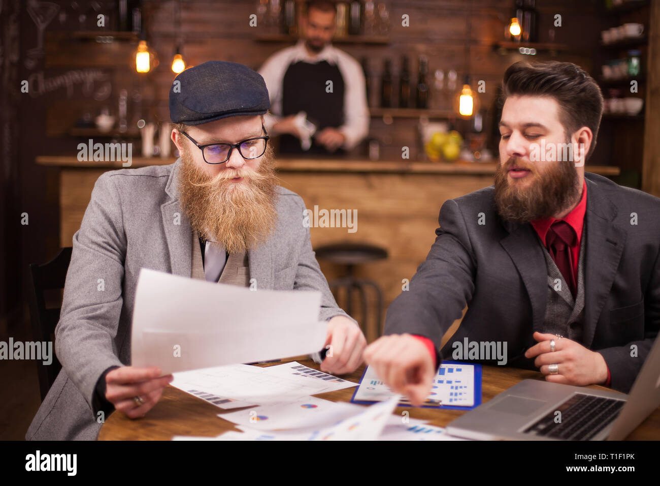 Handsome coworkers reading documents in a coffee shop. Succesful men ...