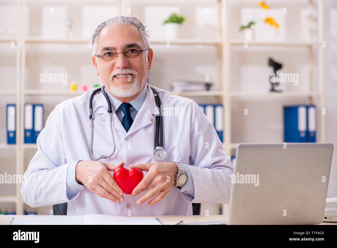 Aged male doctor cardiologist with heart model Stock Photo - Alamy