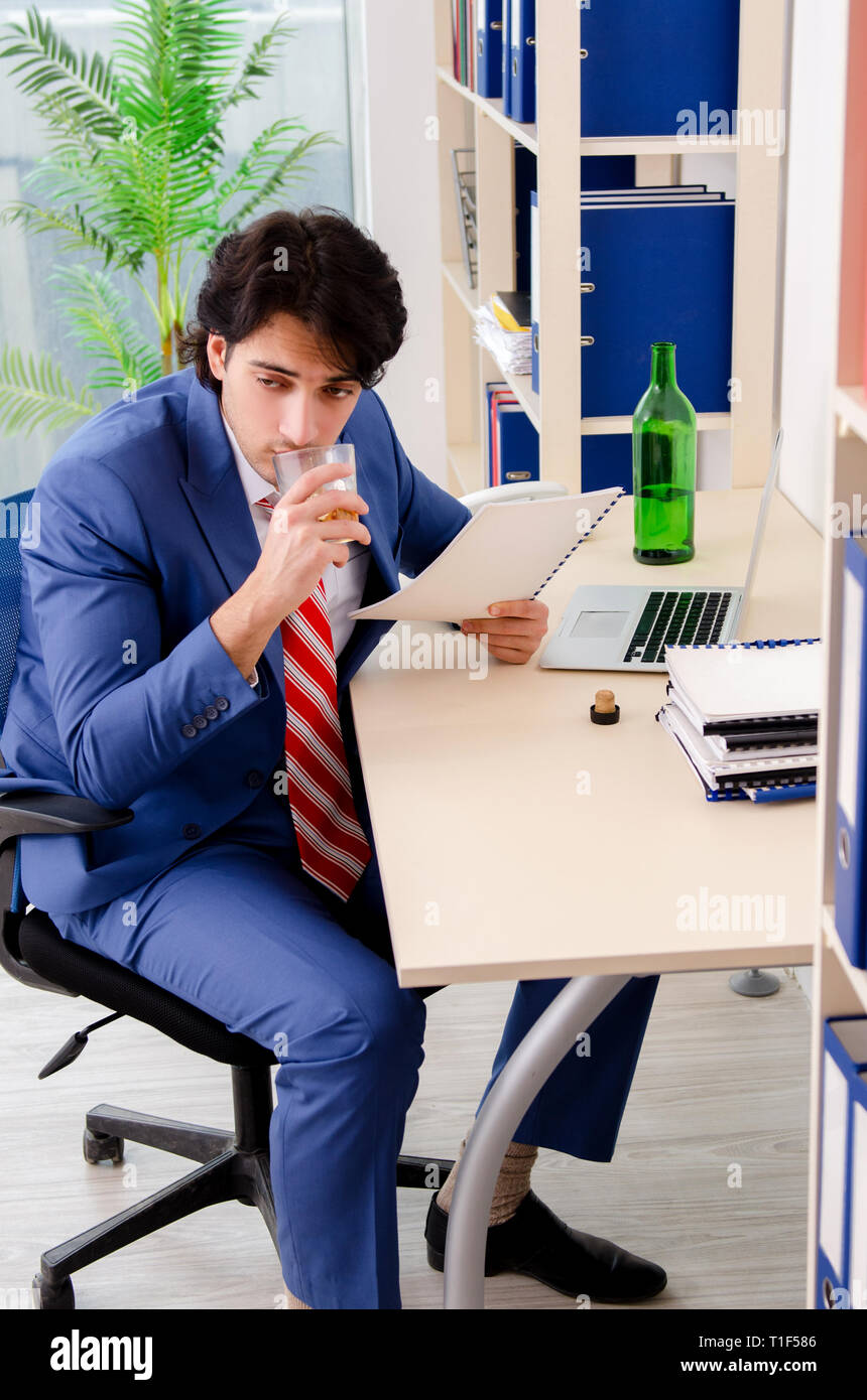 Young businessman employee drinking in the office Stock Photo - Alamy