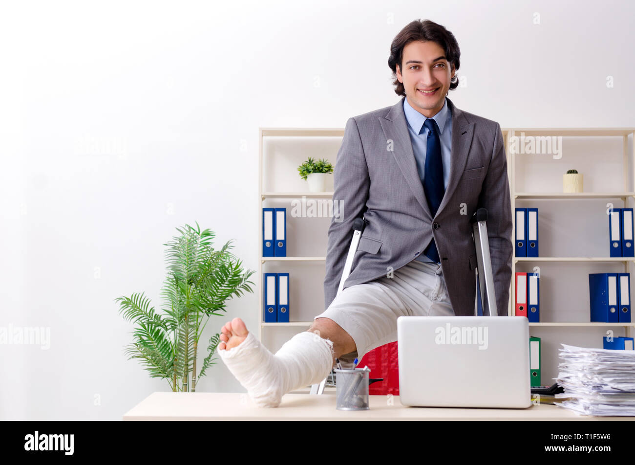 Leg injured employee working in the office Stock Photo - Alamy