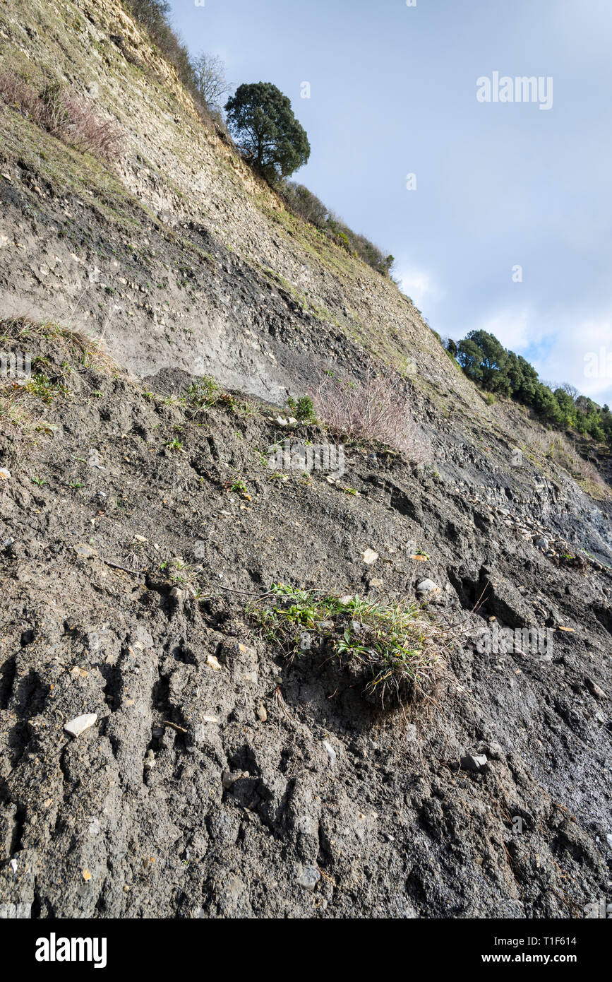 Earth and mud at the base of a tall cliff due to erosion Stock Photo ...