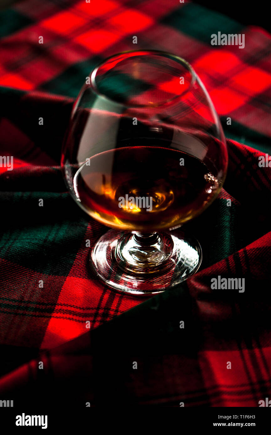 Scottish whiskey in a glass with ice on traditional red with green ...