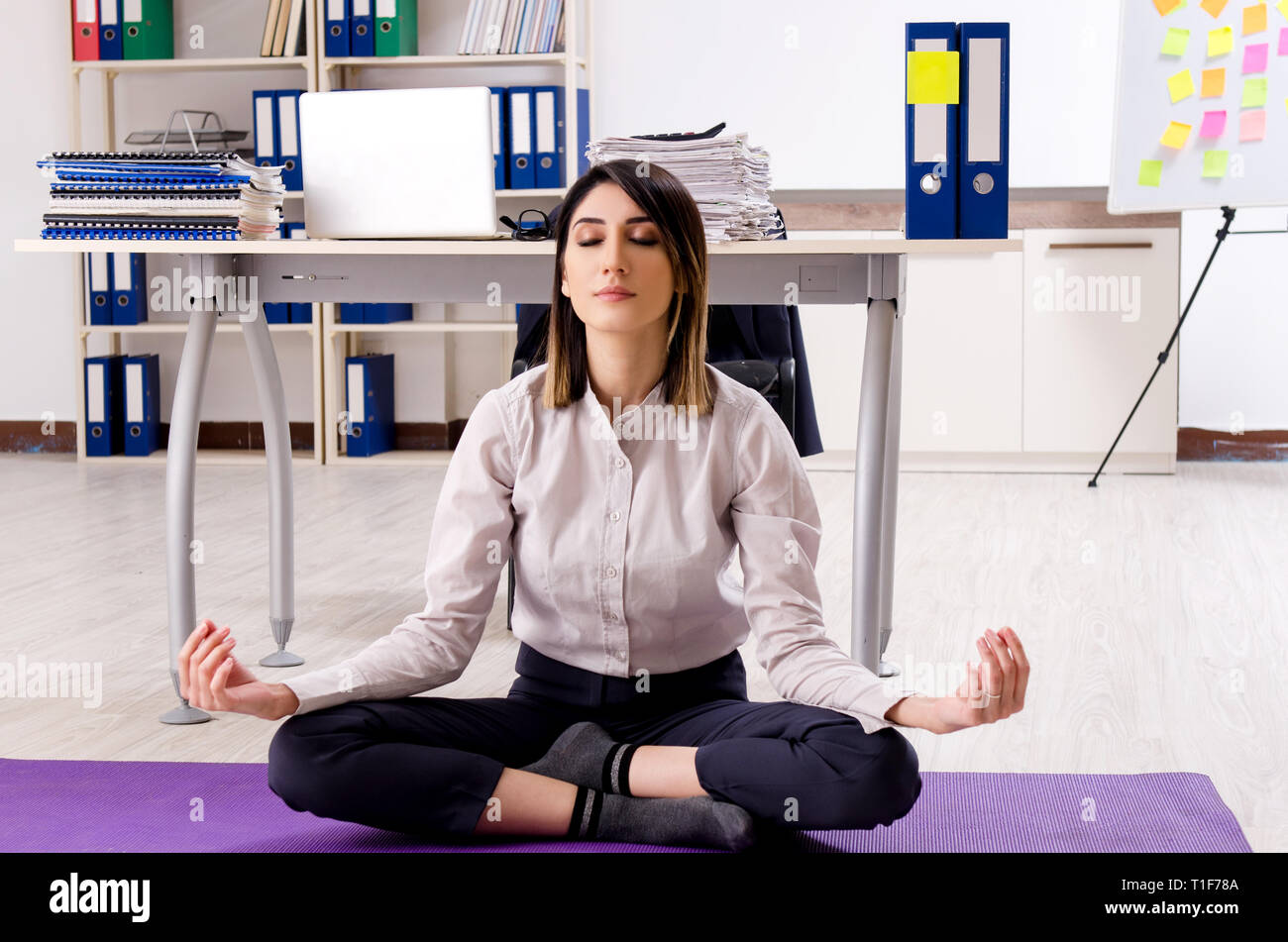 Young female employee doing exercises at workplace Stock Photo - Alamy