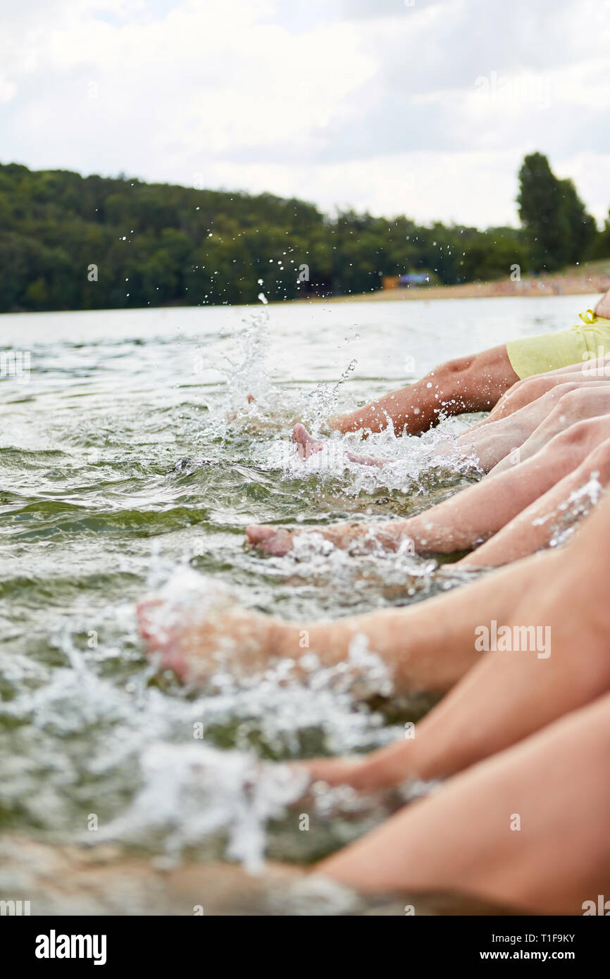 Seniors splashing with their feet in the lake and splash with water in ...