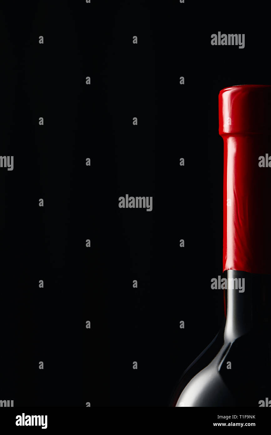 Wine bottle with red wrapper isolated on black Stock Photo - Alamy