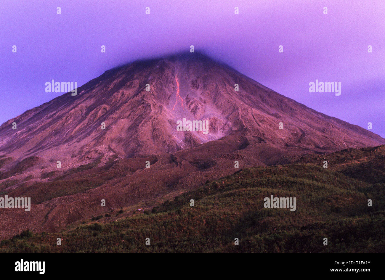 Molten cinder blocks falling down Arenal volcano in Costa Rica at dusk ...