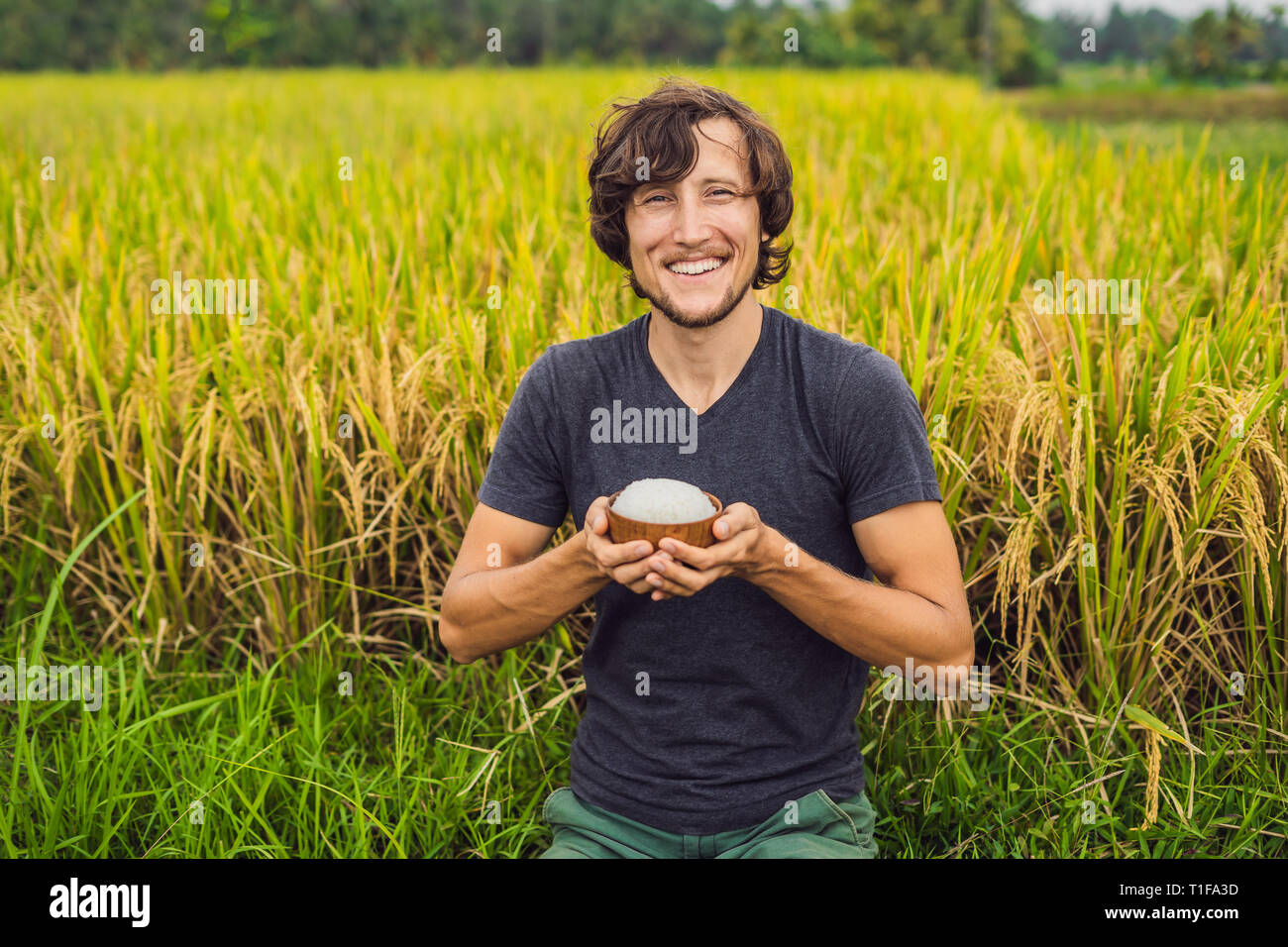 Man is holding a cup of boiled rice in a wooden cup on the background ...
