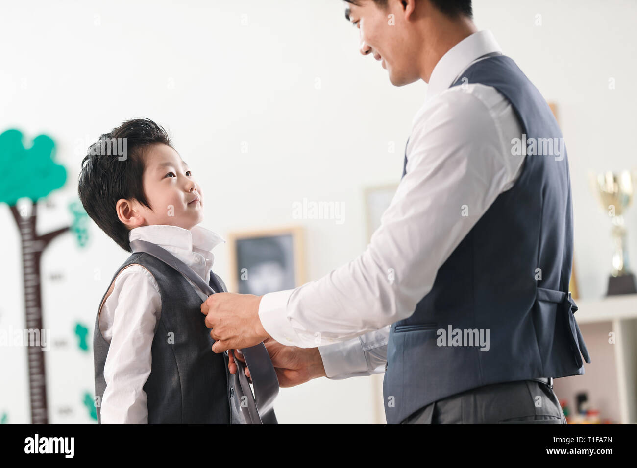 Father help son to wear clothes Stock Photo - Alamy
