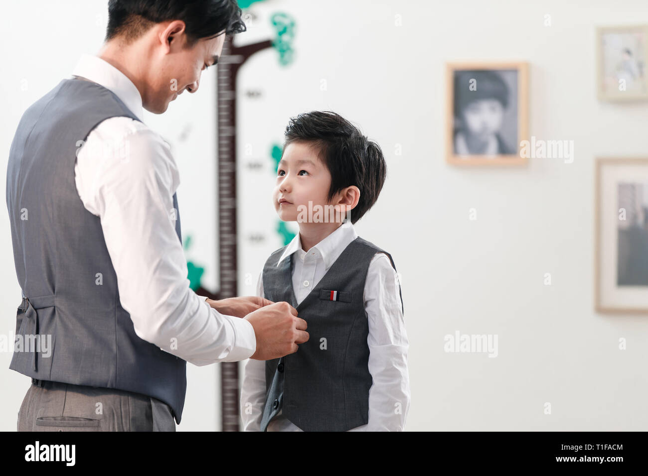 Father help son to wear clothes Stock Photo - Alamy
