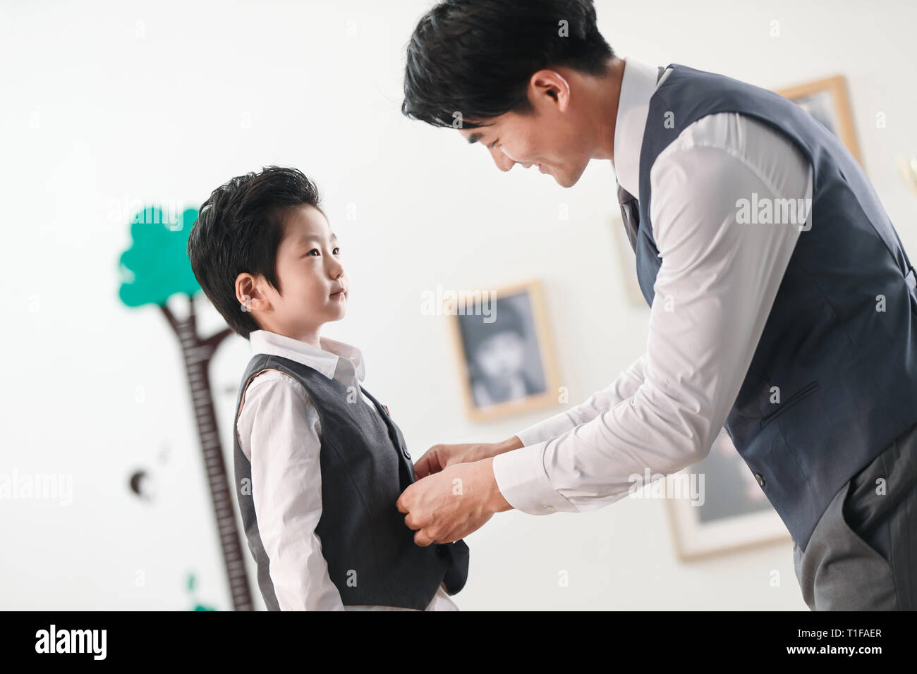 Father help son to wear clothes Stock Photo - Alamy