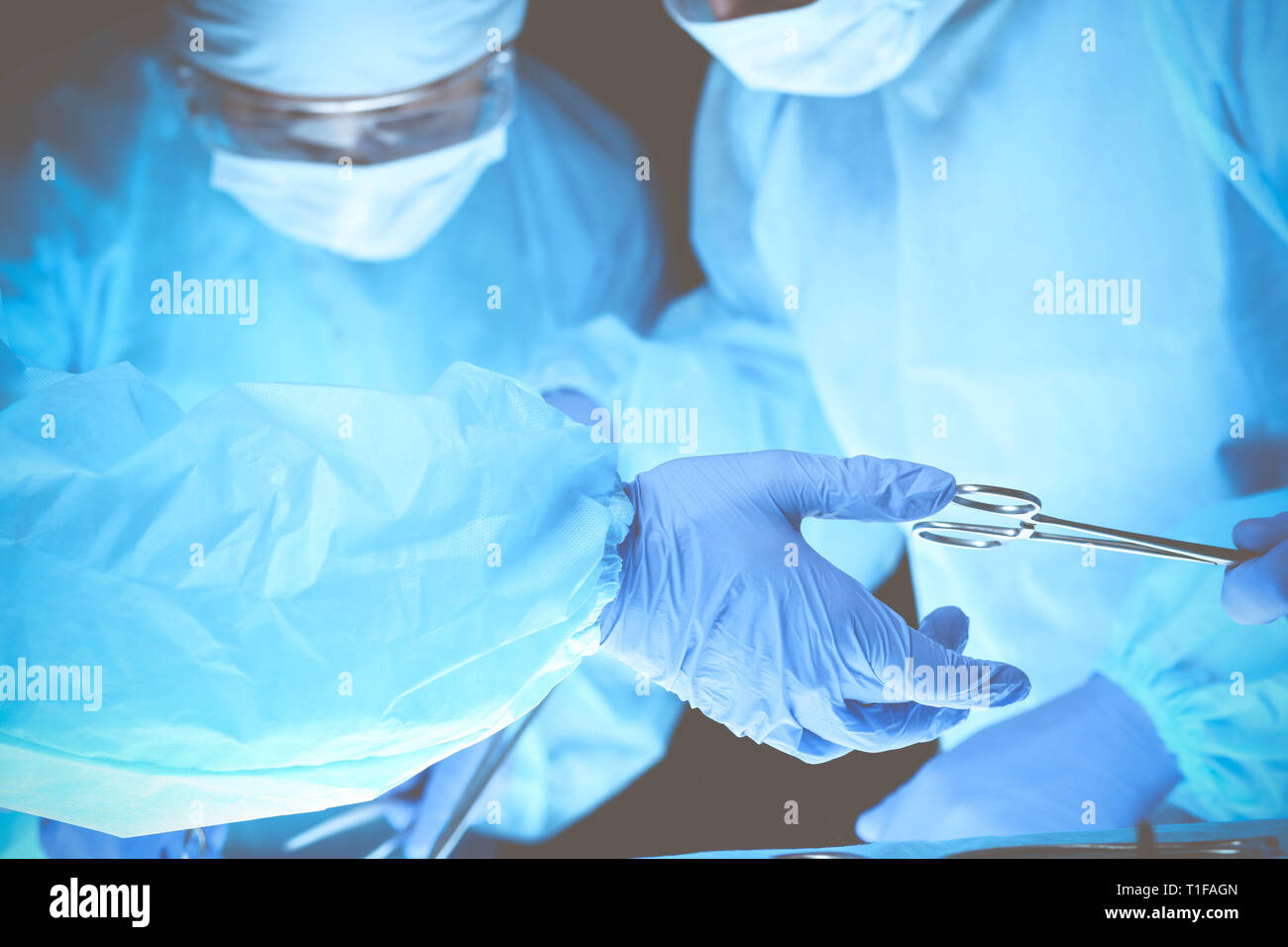 Surgeons hands holding surgical scissors and passing surgical equipment ...