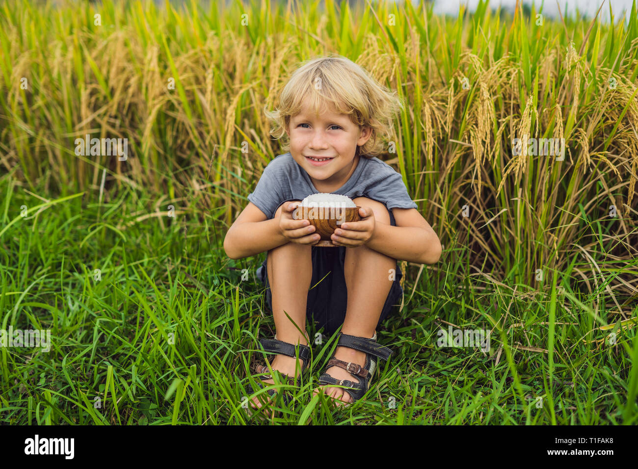 Boy is holding a cup of boiled rice in a wooden cup on the background ...