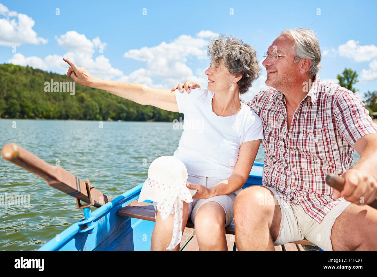 Senior couple in rowboat on the road on a lake in summer on vacation ...