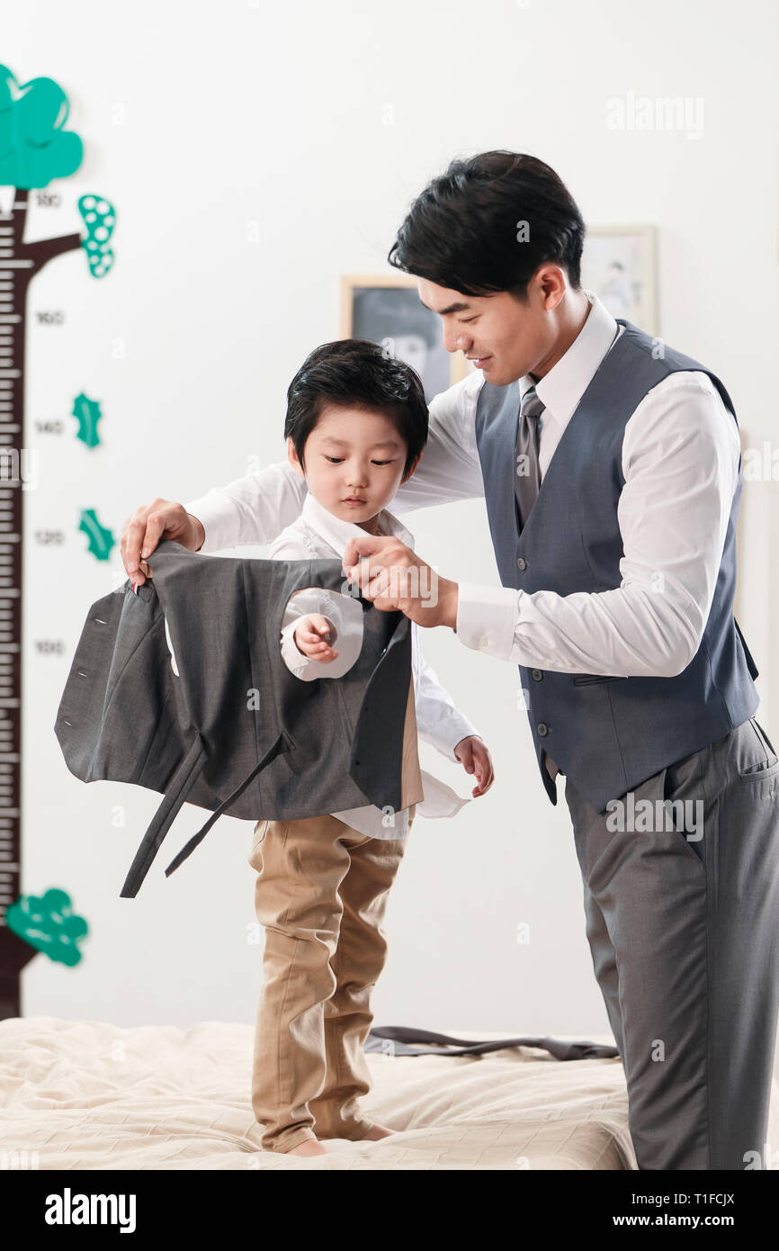 Father help son to wear clothes Stock Photo - Alamy