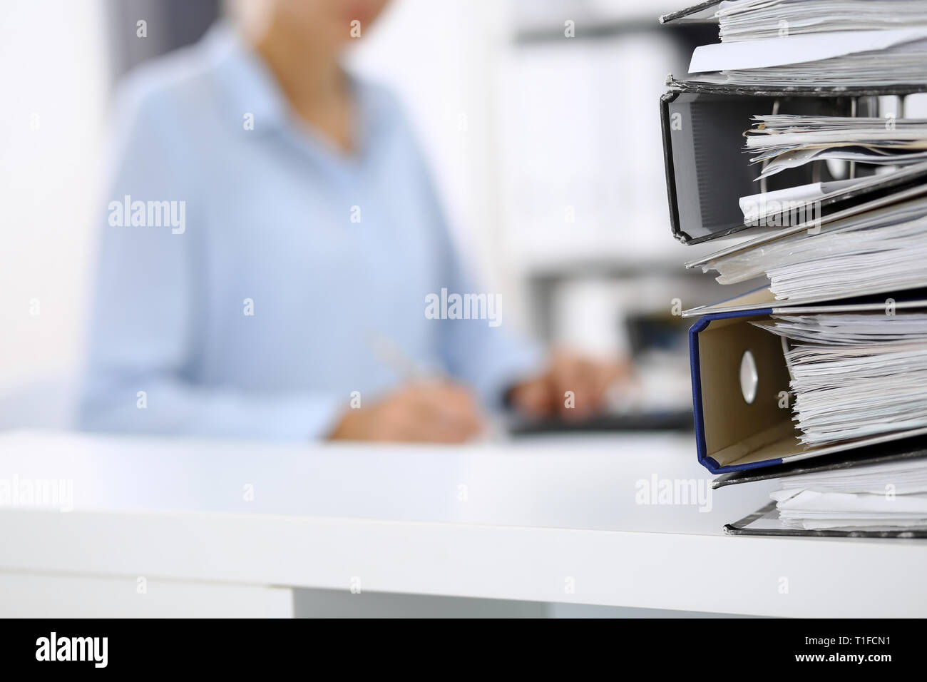 Binders with papers are waiting to be processed by business woman or ...