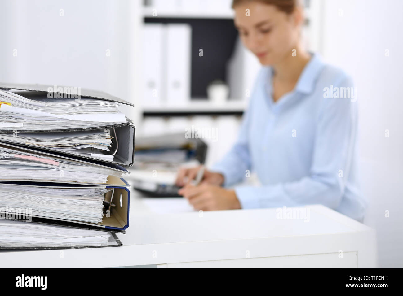 Binders with papers are waiting to be processed by business woman or ...