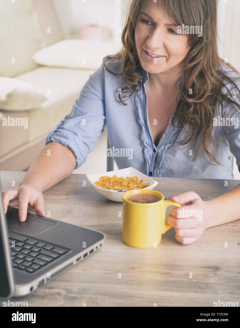Beautiful young woman eating cornflakes and drinking coffe while ...
