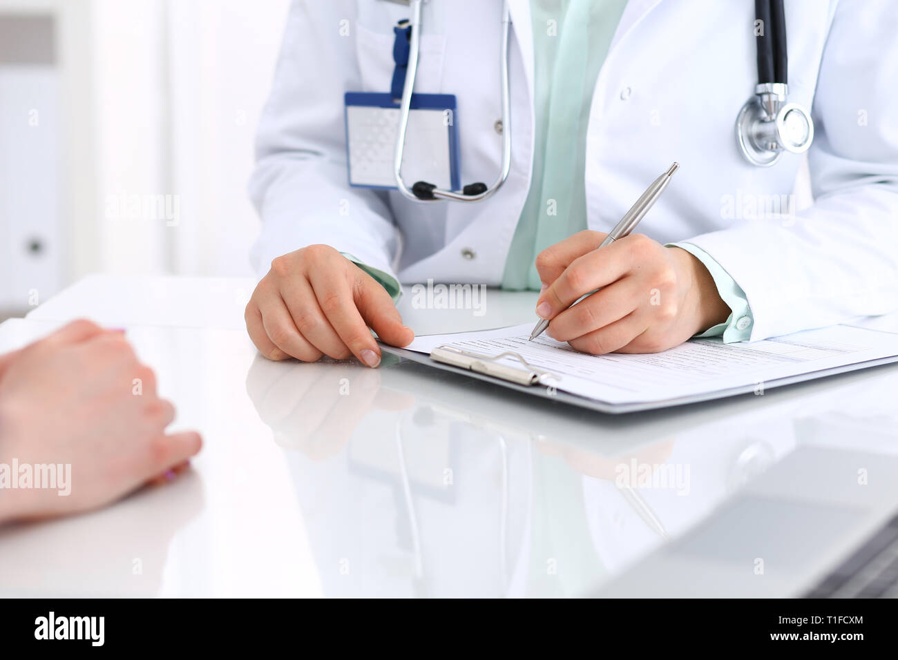 Unknown doctor woman consulting patient while filling up an application ...