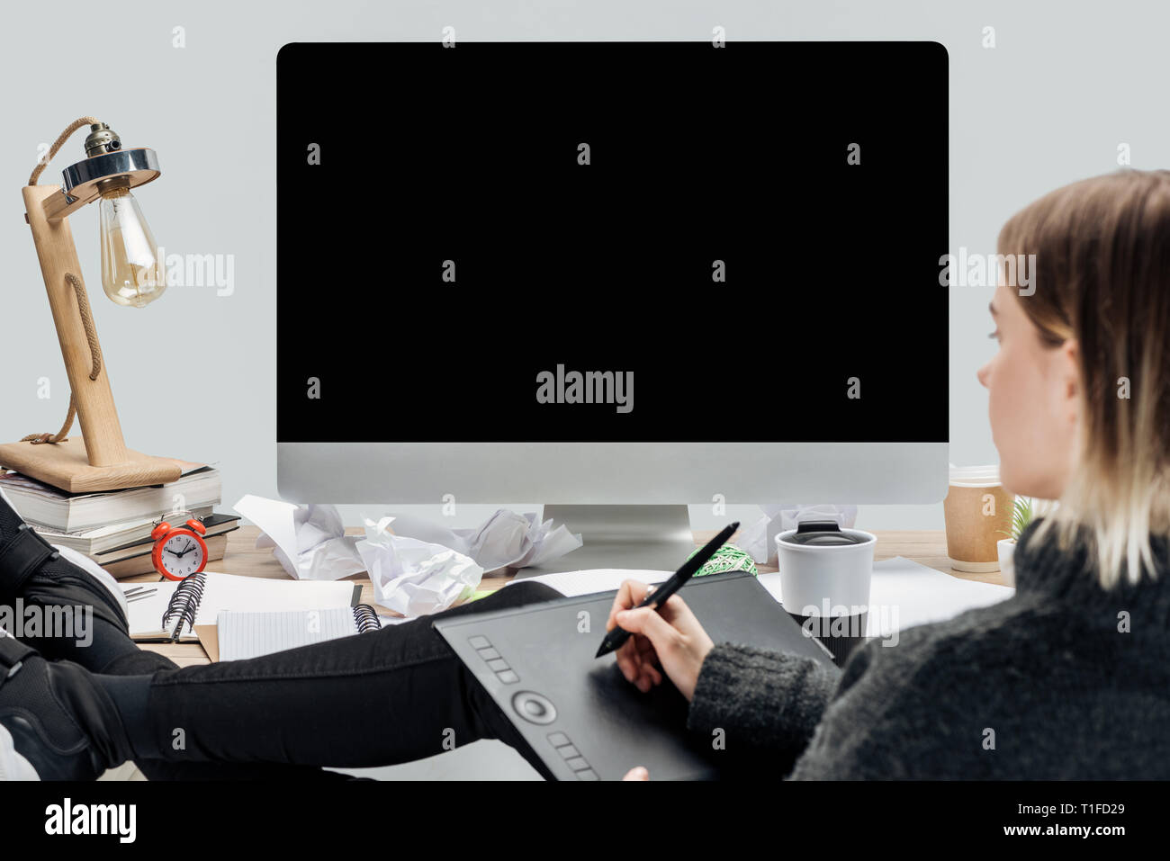 girl sitting at messy workplace with legs on desk and using graphic ...