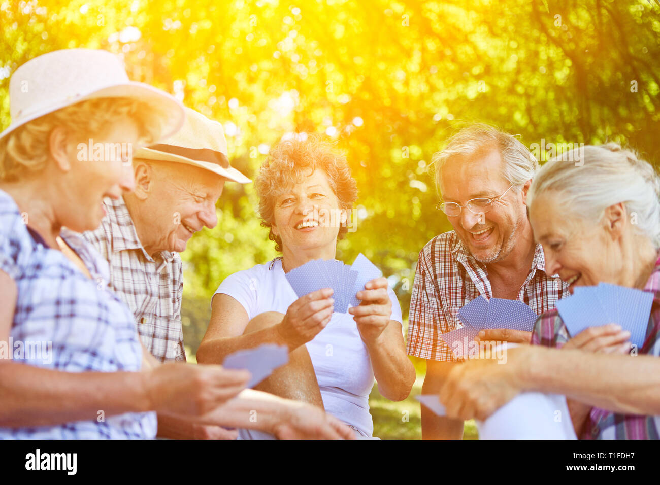 Happy group of seniors together while playing cards in summer Stock ...