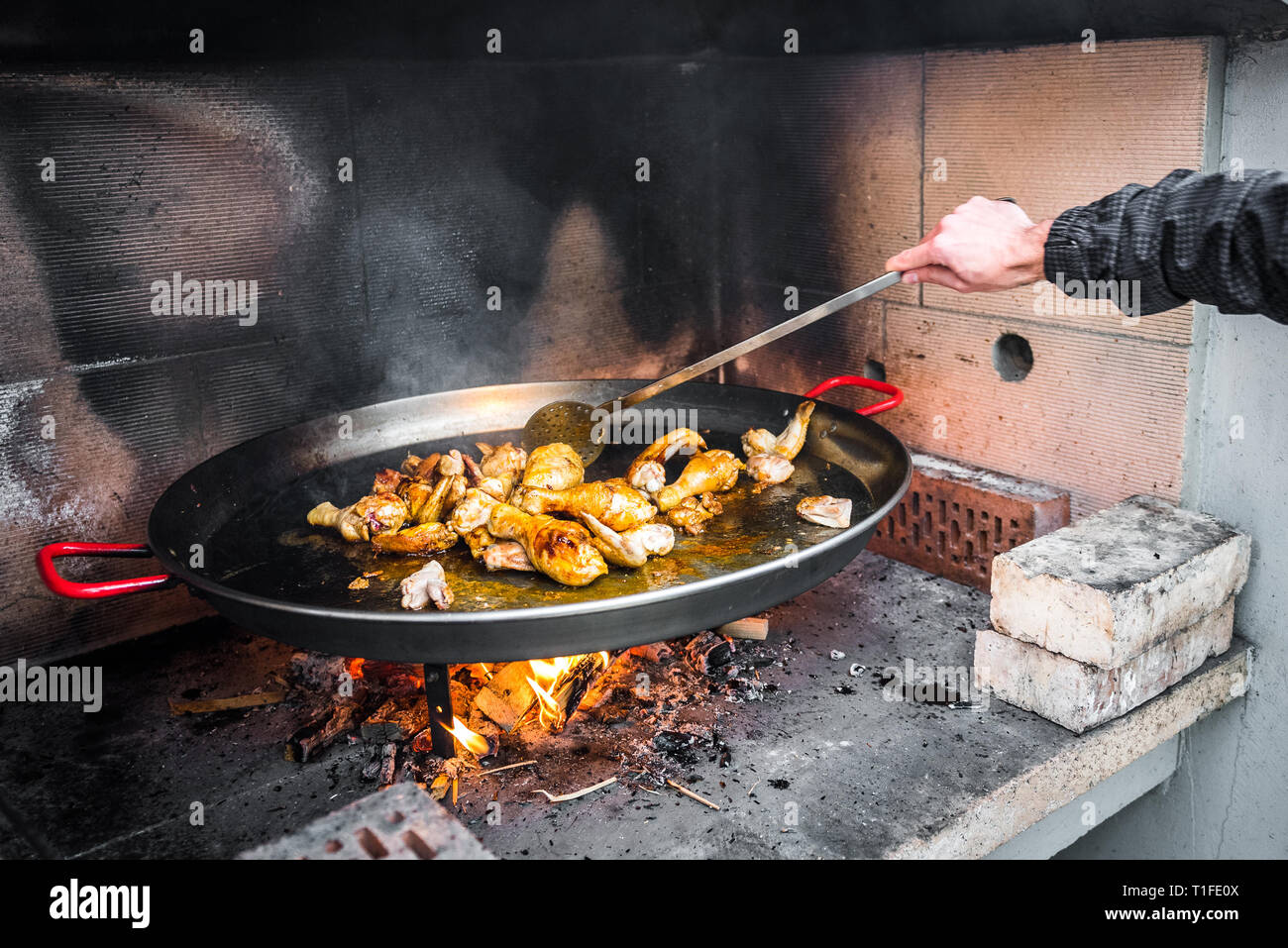 Cooking and making a traditional Spanish Paella over open fire ...