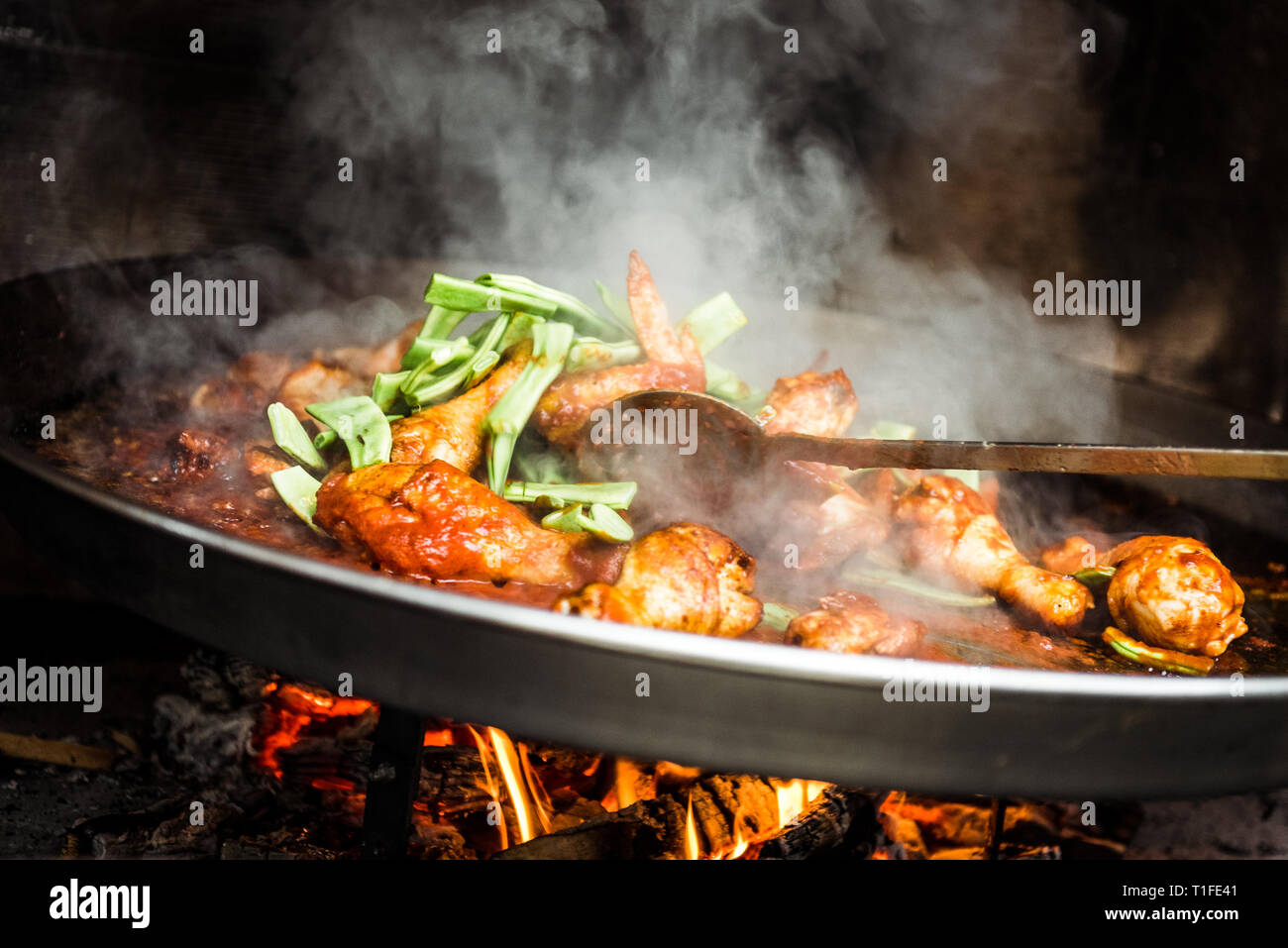 Cooking and making a traditional Spanish Paella over open fire ...