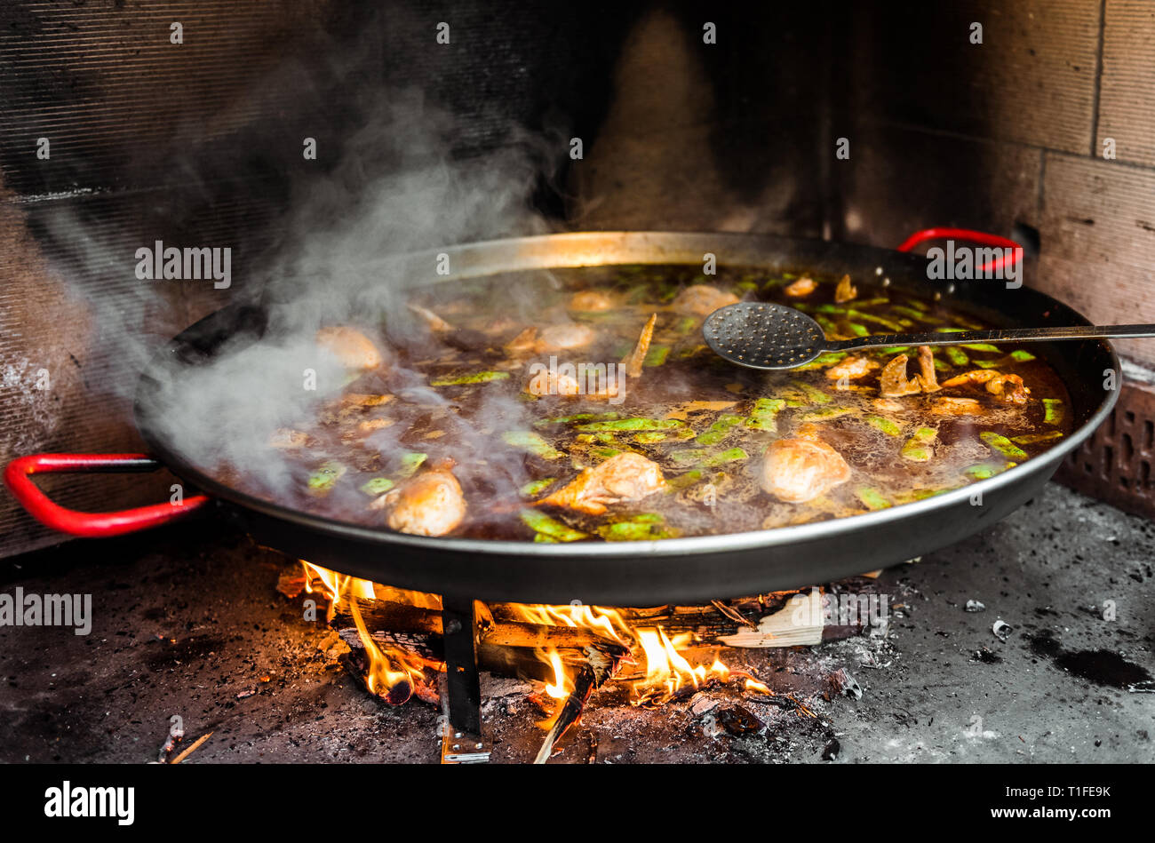 Cooking and making a traditional Spanish Paella over open fire ...