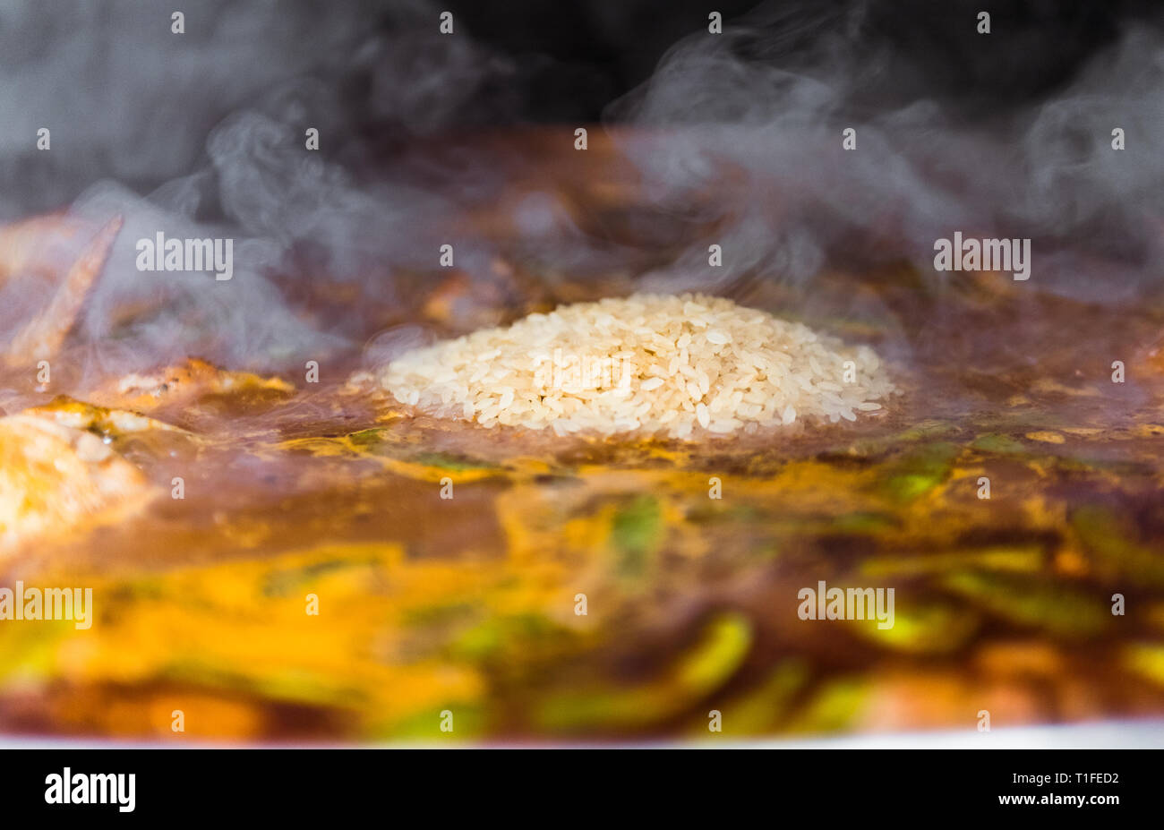 Cooking and making a traditional Spanish Paella over open fire ...