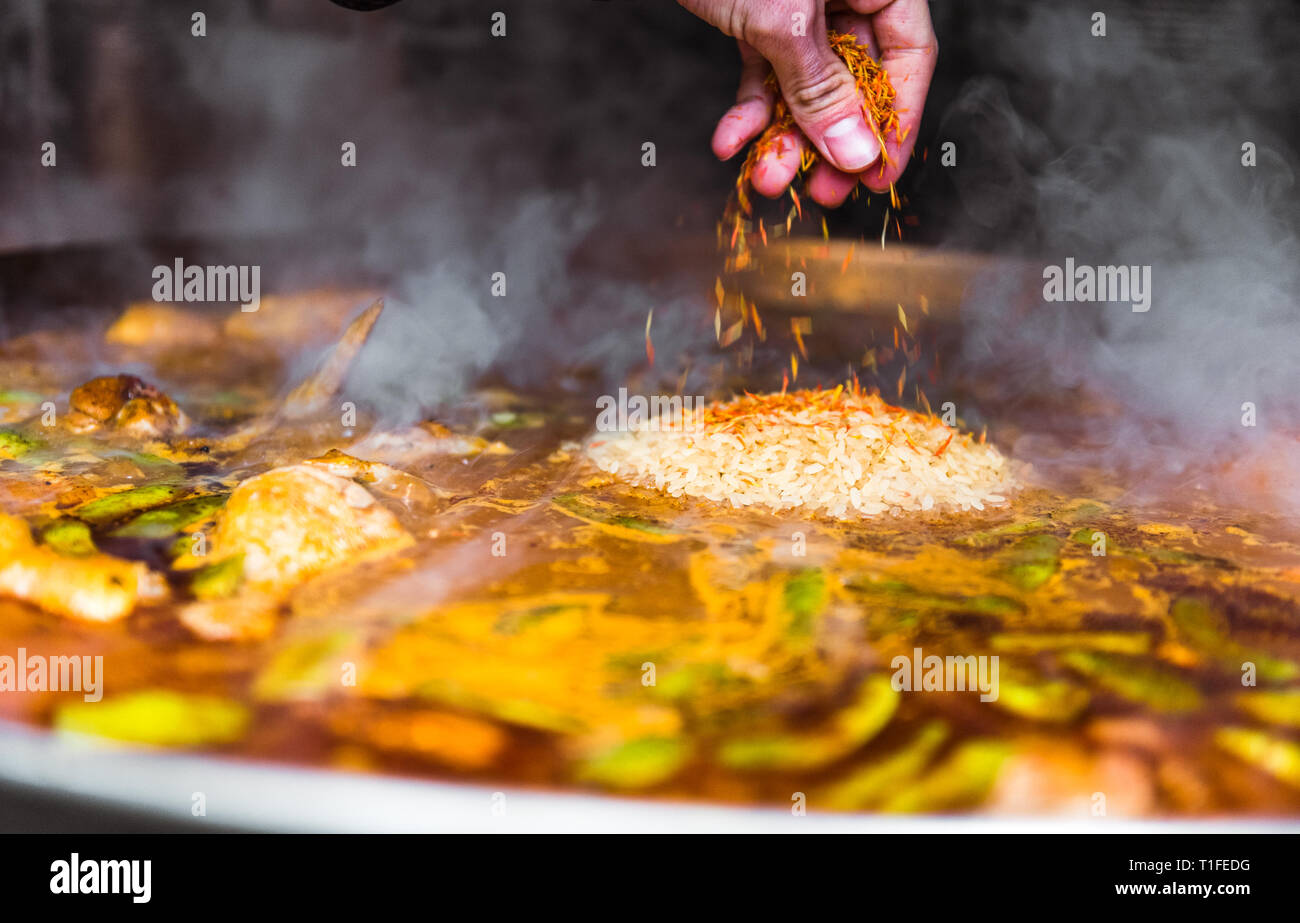 Cooking and making a traditional Spanish Paella over open fire ...