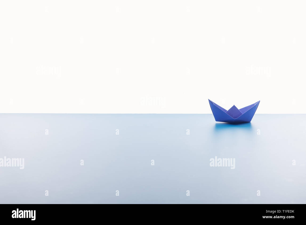 Blue paper boat on light surface on white background Stock Photo - Alamy