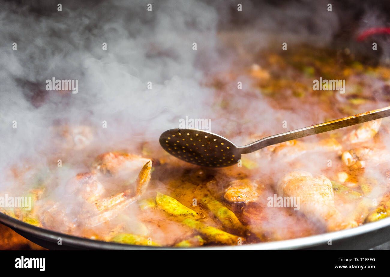 Cooking and making a traditional Spanish Paella over open fire ...