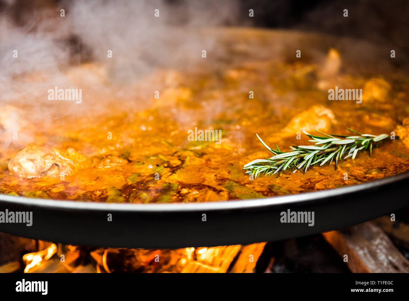Cooking and making a traditional Spanish Paella over open fire ...