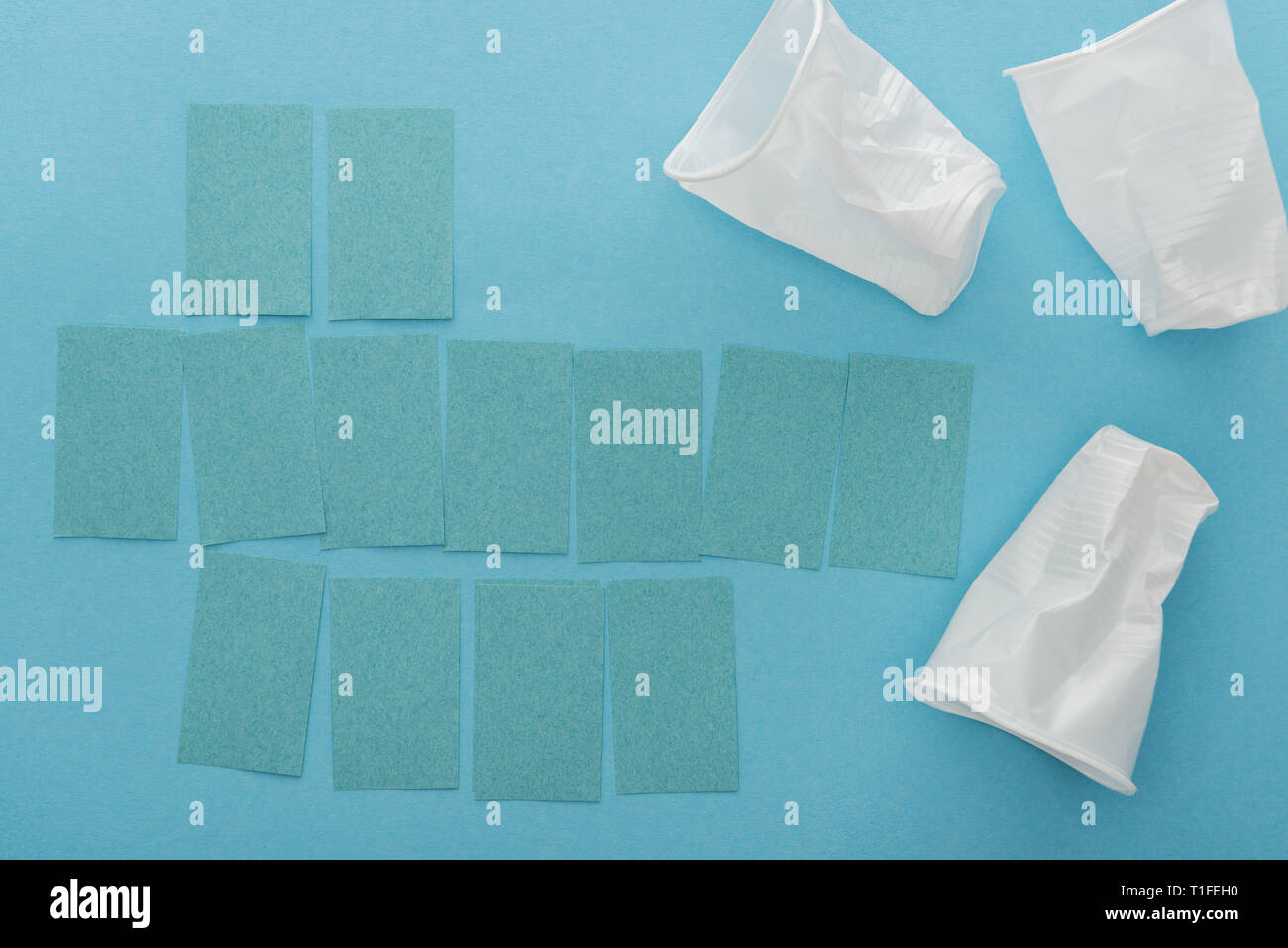 top view of white plastic cups and empty sticky notes on blue ...