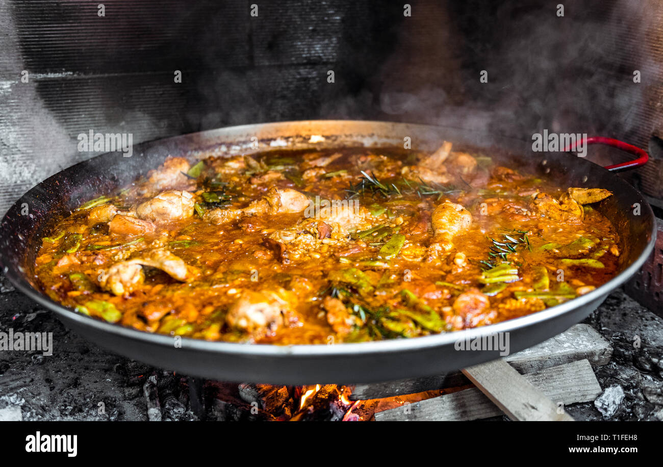 Cooking and making a traditional Spanish Paella over open fire ...