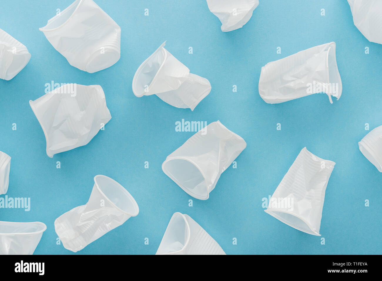 top view of white, crumpled and plastic cups on blue background Stock ...