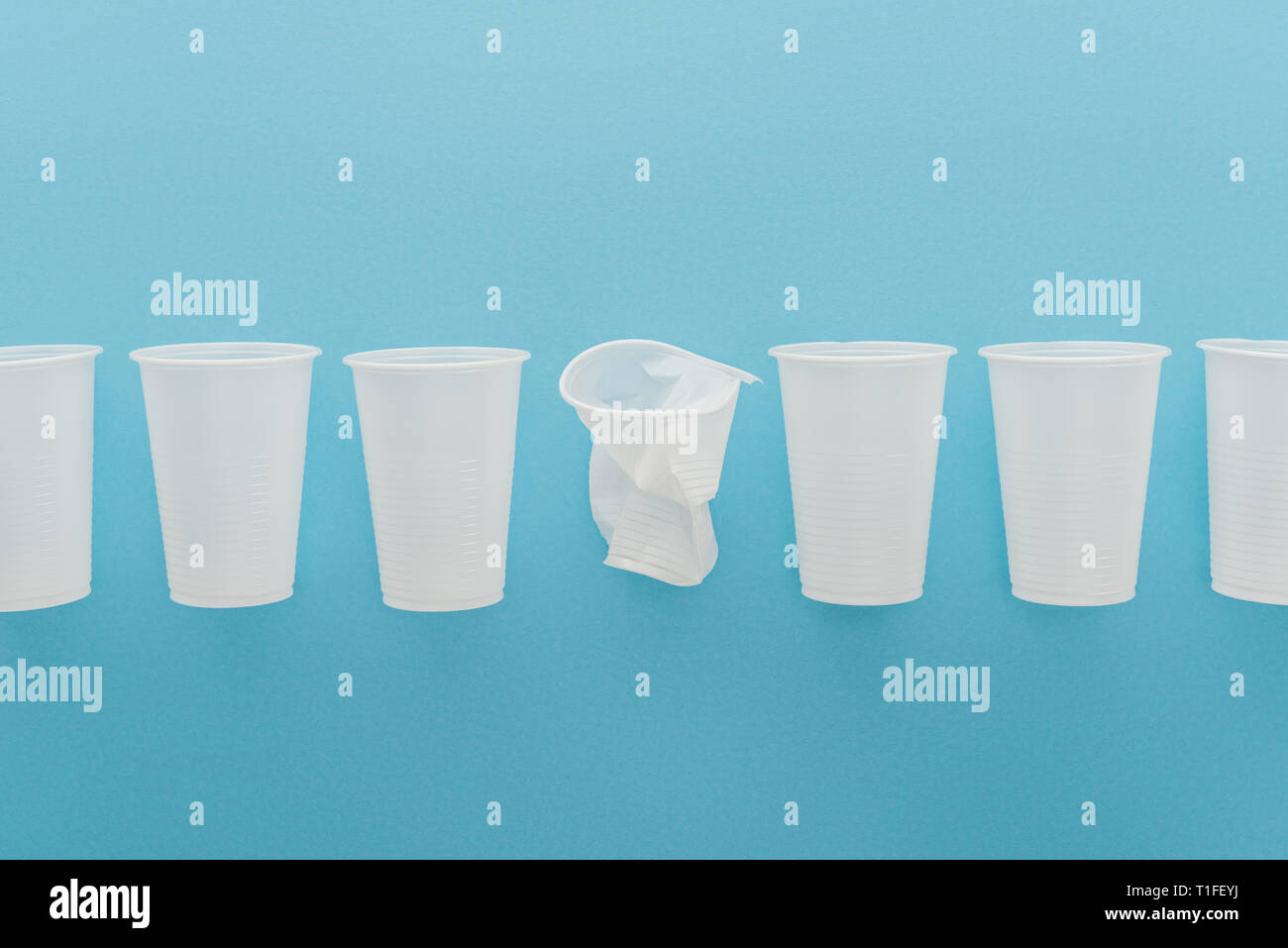 flat lay with white plastic cups on blue background with copy space ...