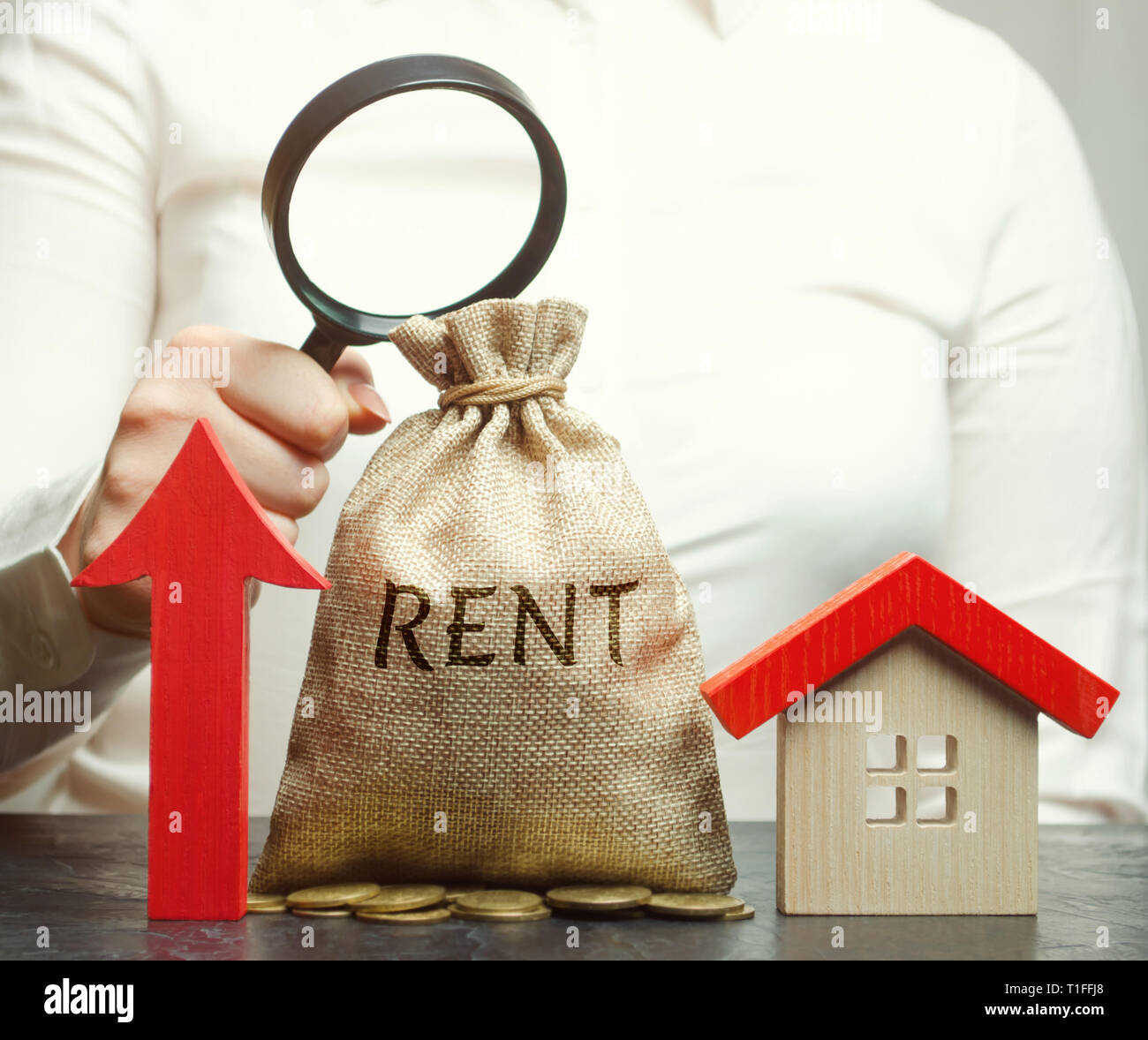 A female hand is holding a magnifying glass over a money bag with the ...