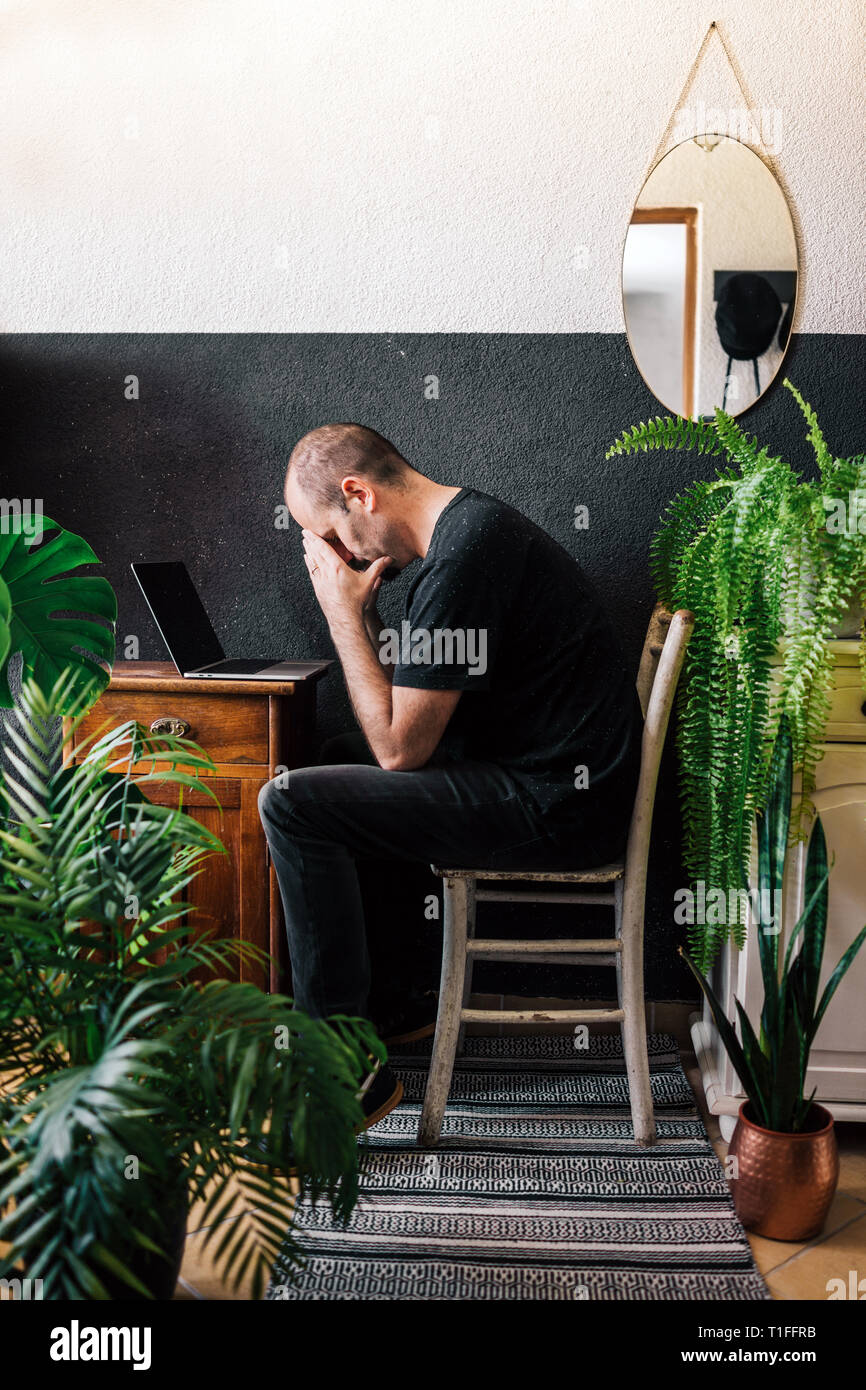 Depressed man in front of his laptop Stock Photo - Alamy