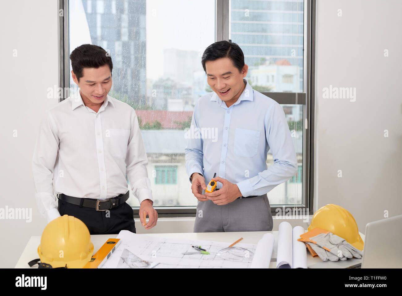 Two architects standing at a desk and discussing a project Stock Photo ...