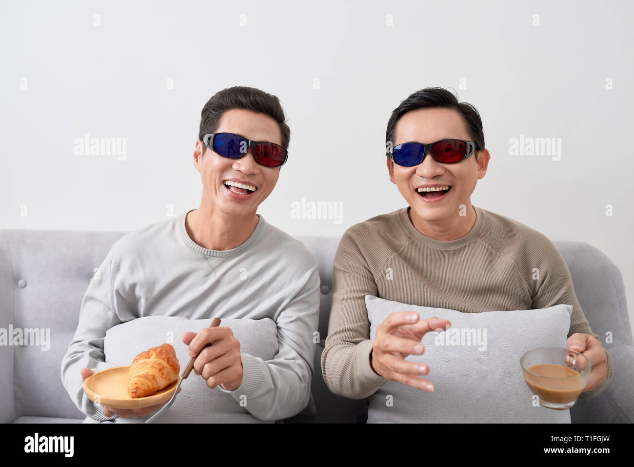 exciting young man watch three-dimensional LCD TV with eye glass in a ...