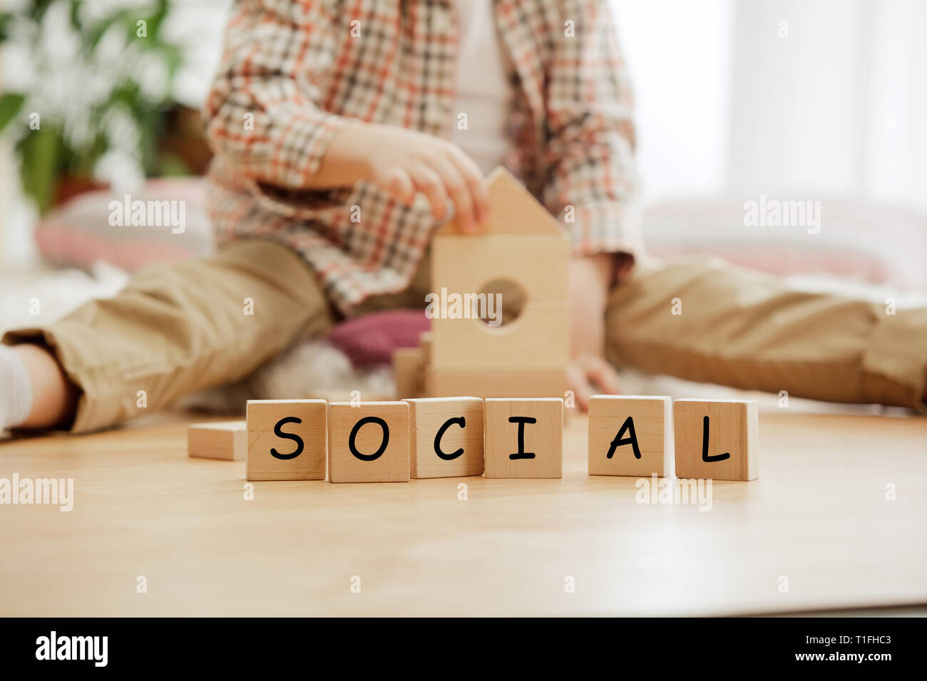 Wooden cubes with word SOCIAL in hands of little boy at home ...