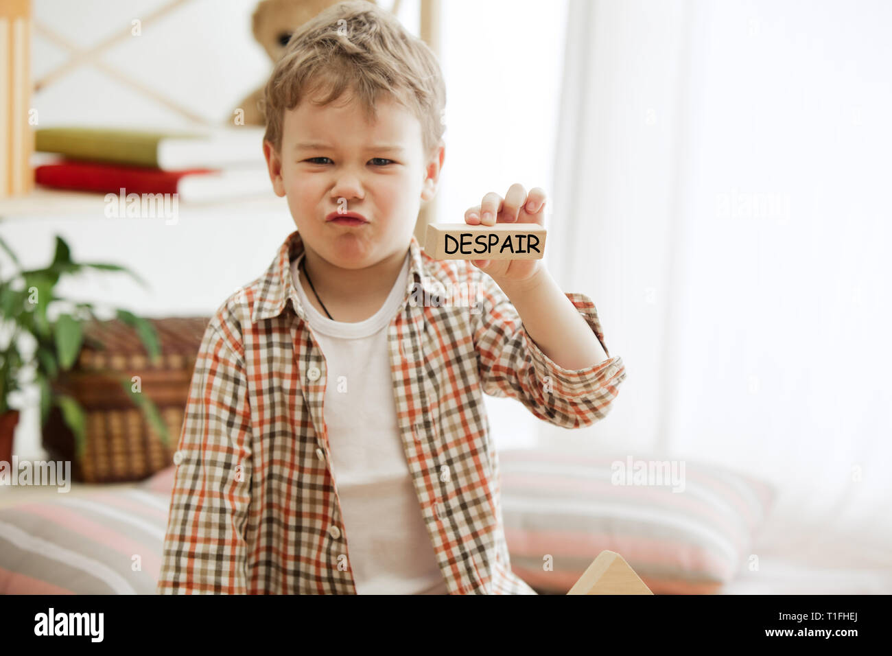 Wooden cubes with word despair in hands of little boy at home ...