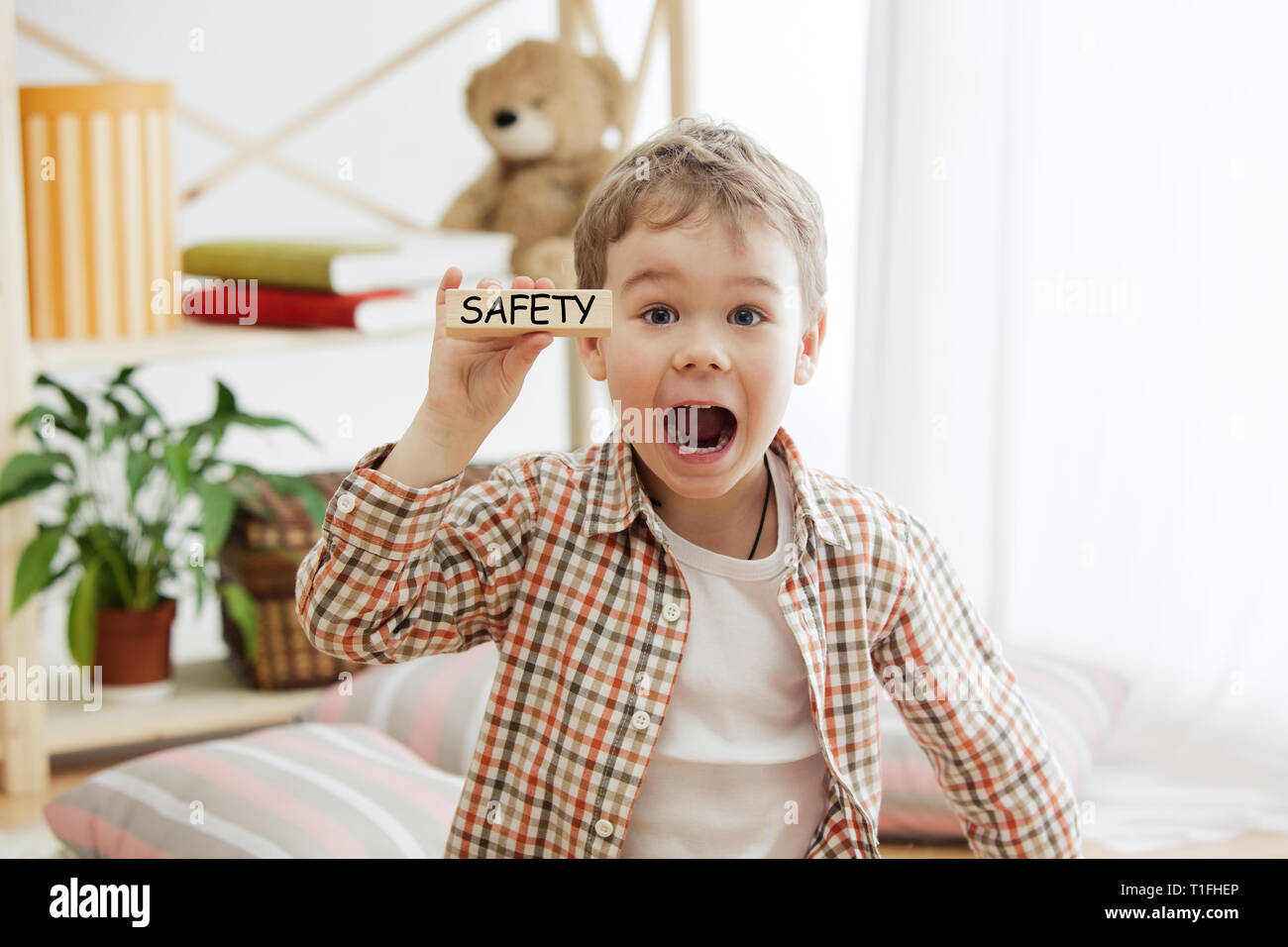 Wooden cubes with word safety in hands of happy smiling little boy at ...