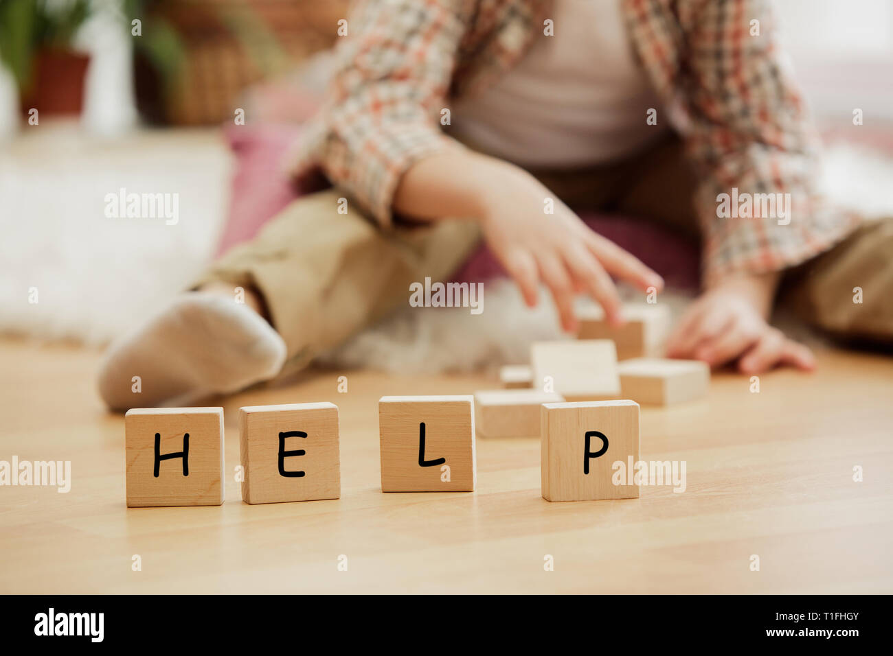 Wooden cubes with word HELP in hands of little boy at home. Conceptual ...